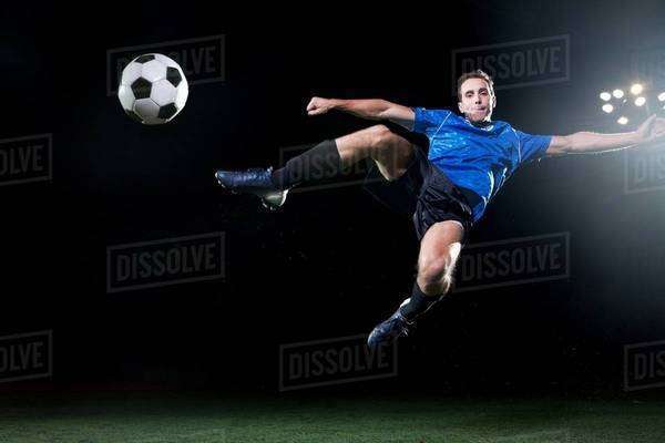 Young soccer player leaping into air to kick ball - Royalty-free Stock ...