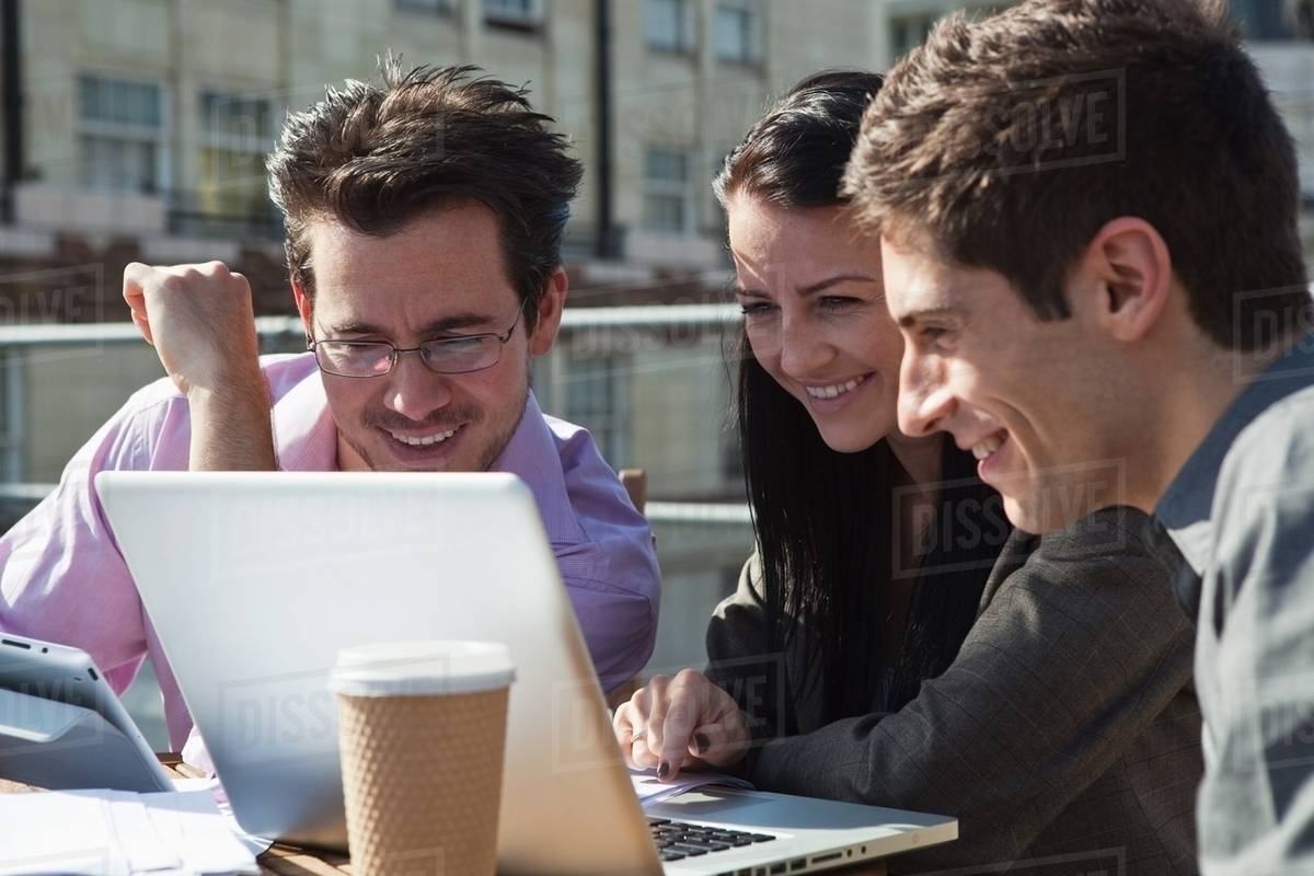 Three people looking at a laptop - Royalty-free Stock Photo | Dissolve