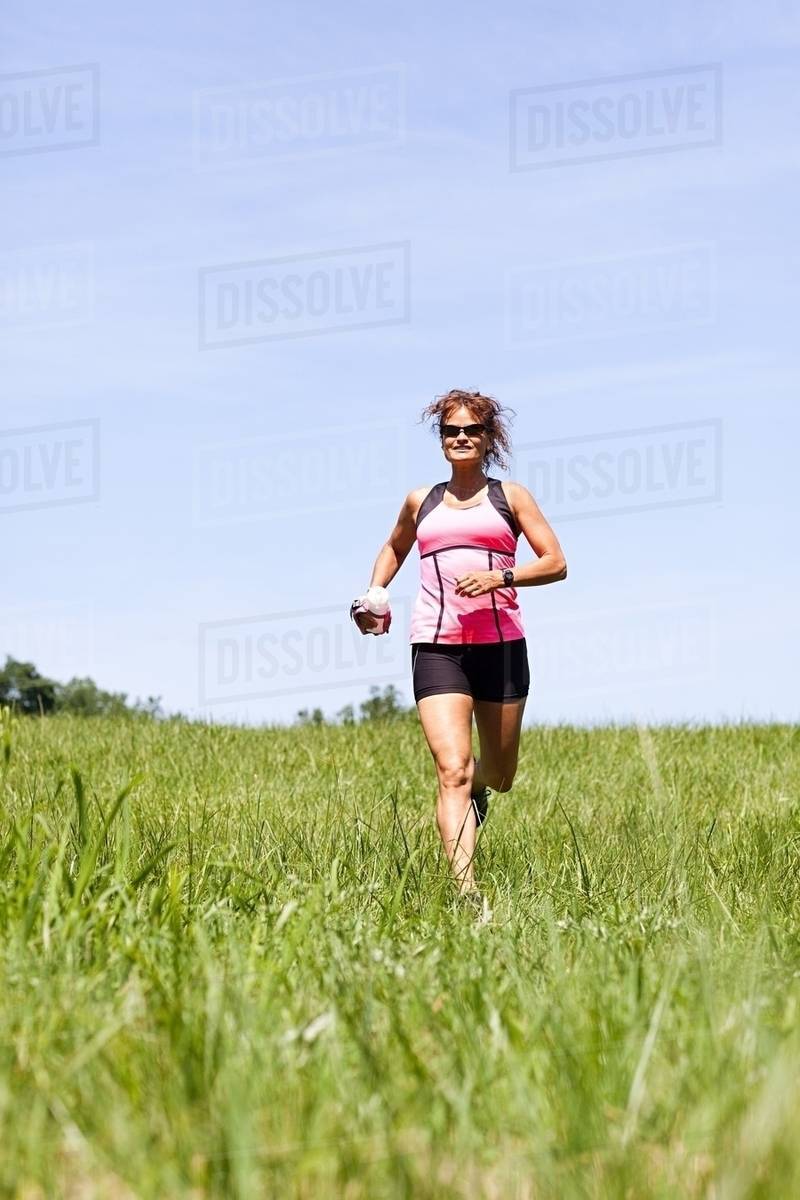 Woman running through field - Stock Photo - Dissolve