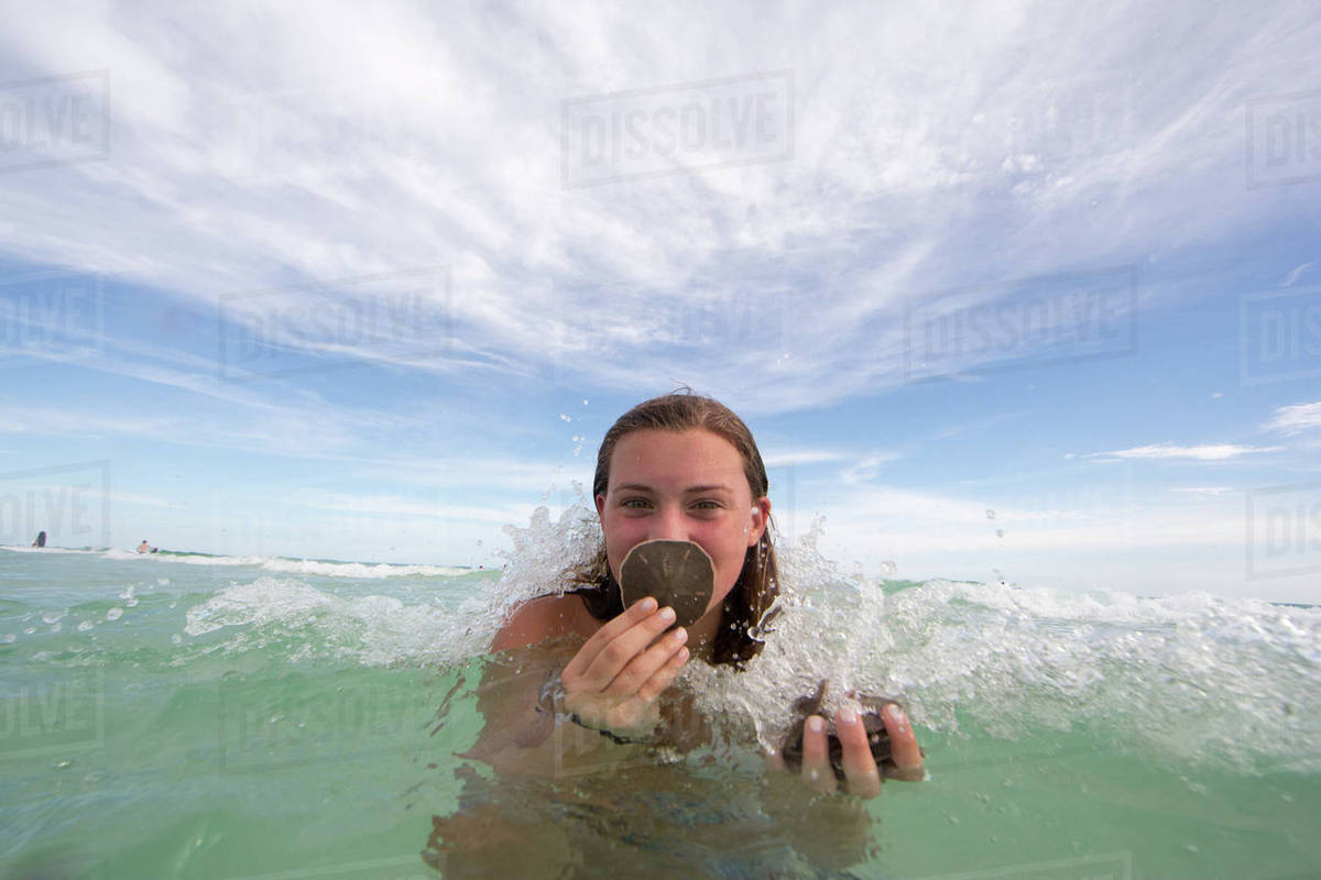 Portrait of young woman in water, holding shells - Stock Photo - Dissolve