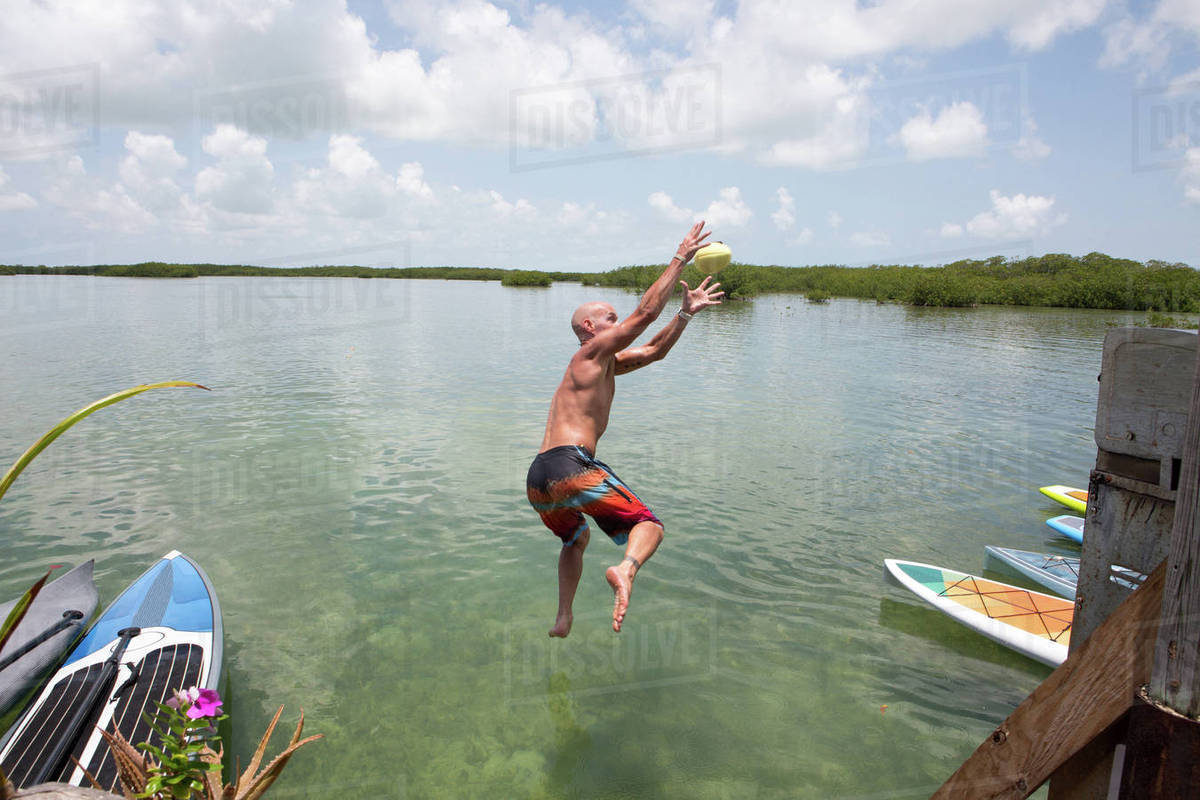 Mature man jumping into water, mid air - Royalty-free Stock Photo ...