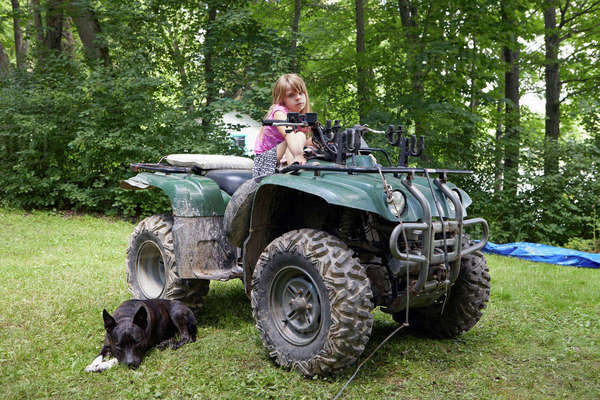 Portrait of girl sitting on quad bike, dog relaxing beside - Royalty ...