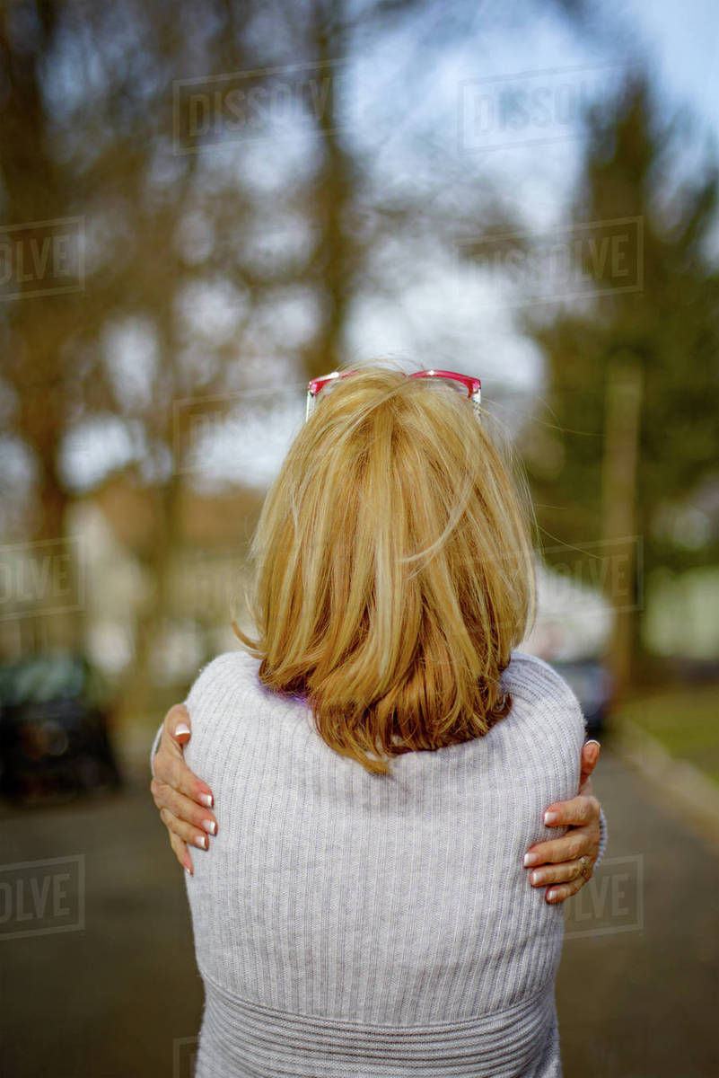 Rear view of mature in park hugging herself - Royalty-free Stock Photo ...