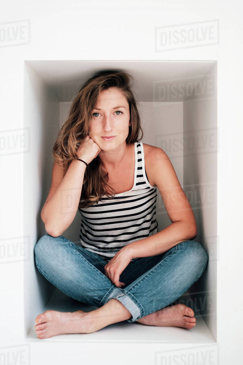 Portrait of young woman sitting in box - Stock Photo - Dissolve