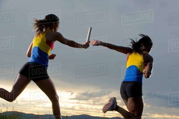 Female relay racers passing baton - Royalty-free Stock Photo | Dissolve