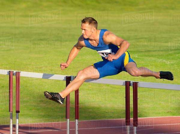 Male hurdler clearing hurdle - Stock Photo - Dissolve