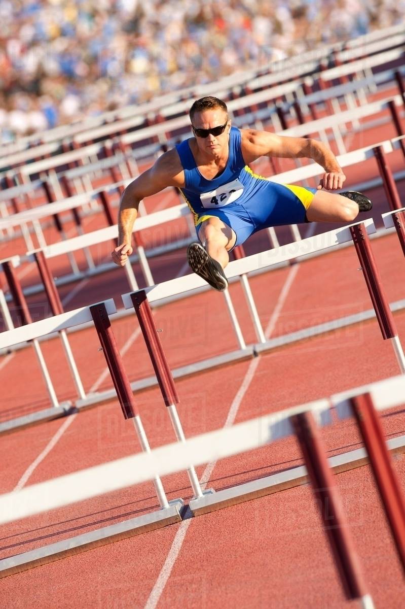 Male hurdler clearing hurdles - Stock Photo - Dissolve