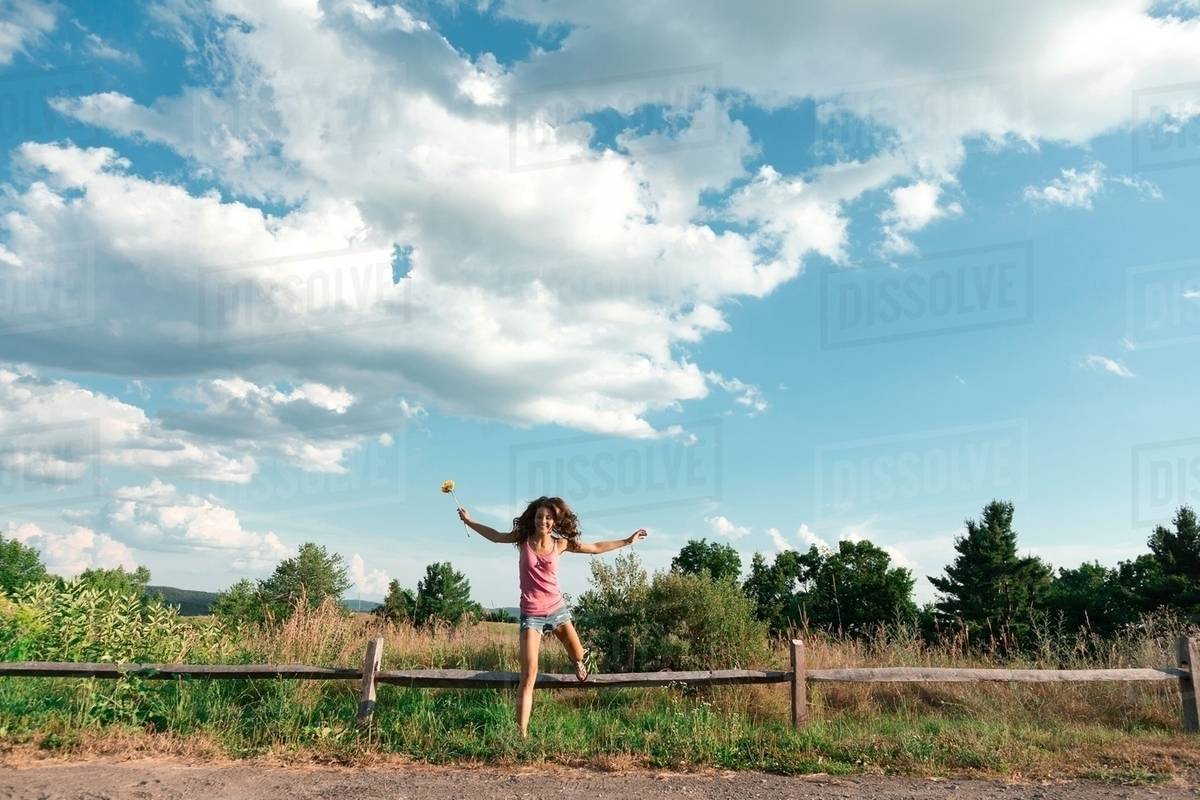 Teenage girl jumping off wooden fence - Royalty-free Stock Photo | Dissolve
