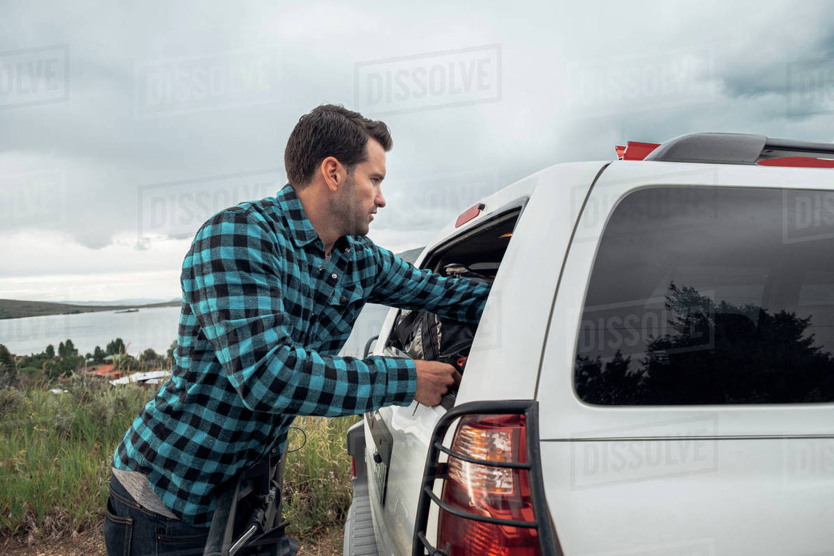 Mid adult man reaching into window of parked car, Silverthorne ...