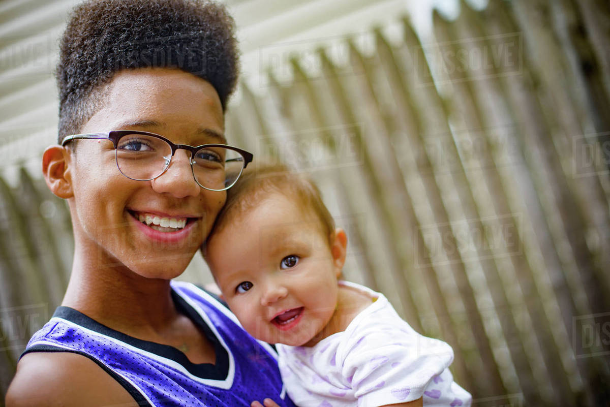 Portrait of teenage boy carrying baby girl in arms - Royalty-free Stock ...