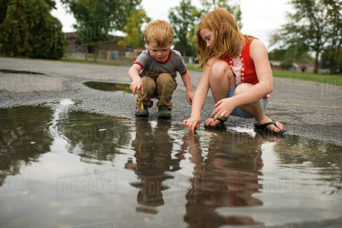 Children playing in puddle on road - Royalty-free Stock Photo | Dissolve