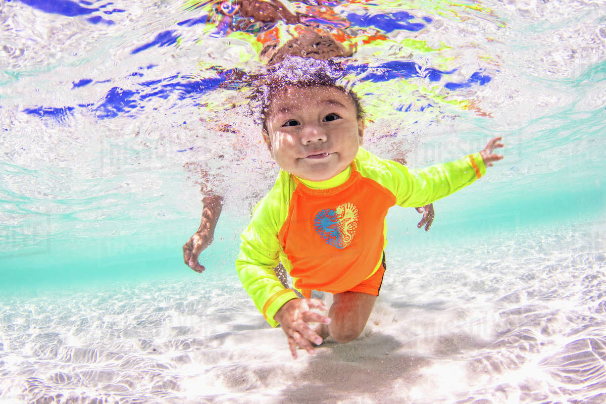 Baby swimming in ocean - Stock Photo - Dissolve