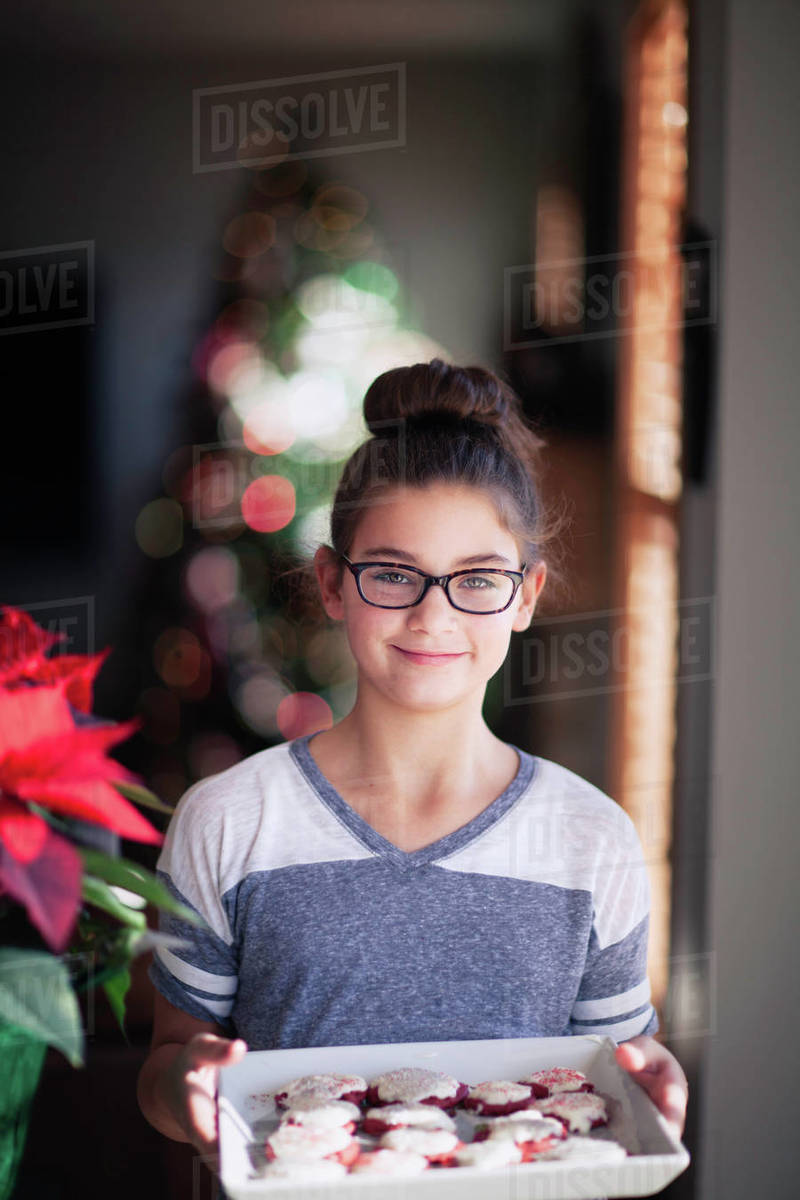 Girl holding tray of homemade christmas cookies in living room ...