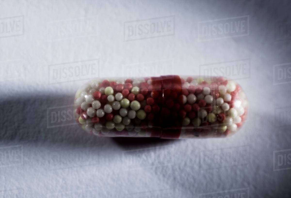 Capsule containing tiny pills - Stock Photo - Dissolve