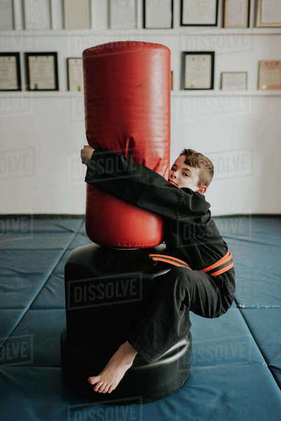 Boy clinging onto punch bag in martial arts studio - Royalty-free Stock ...