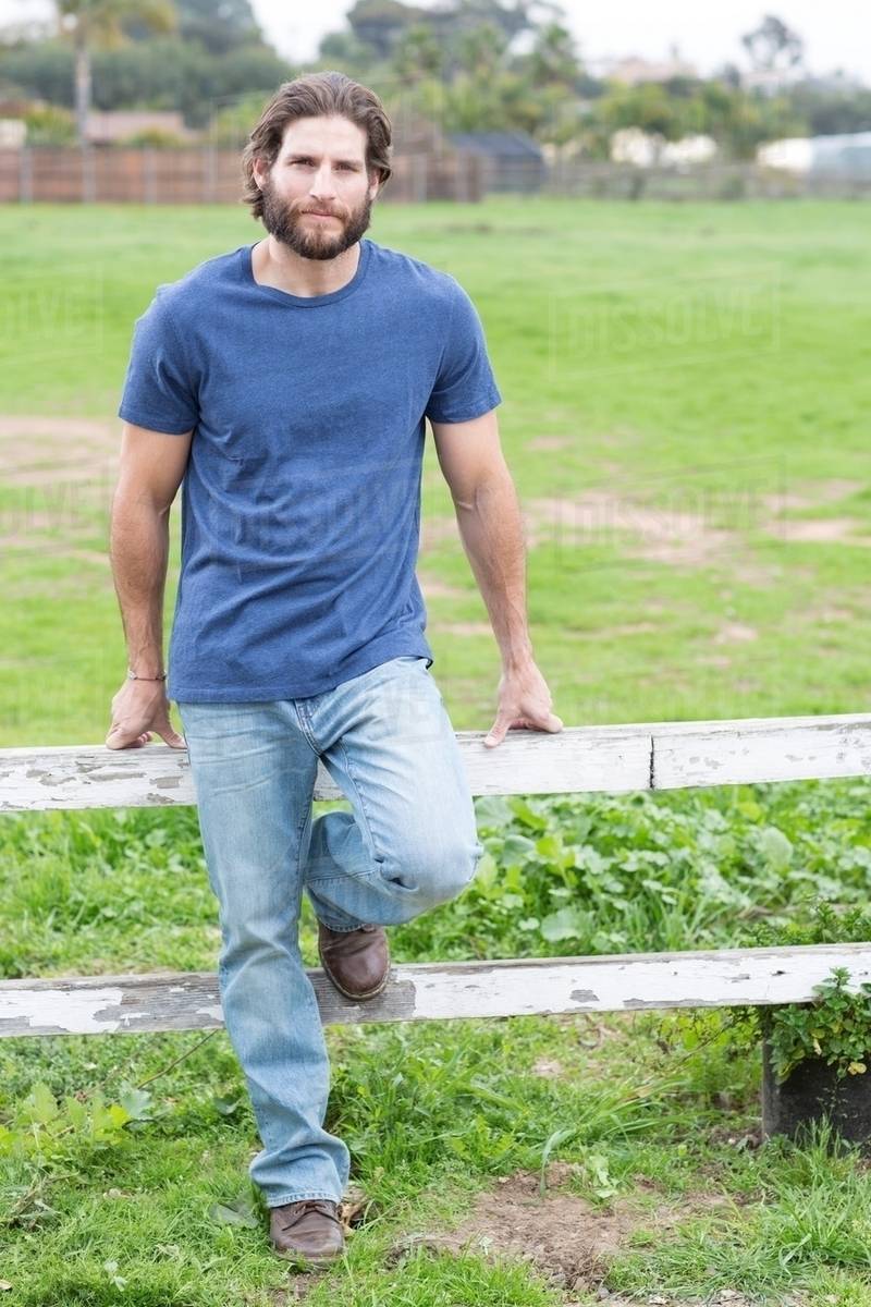 Man leaning on wooden fence - Stock Photo - Dissolve