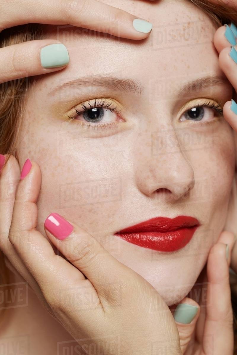 Close up of young woman with hands around her face - Stock Photo - Dissolve