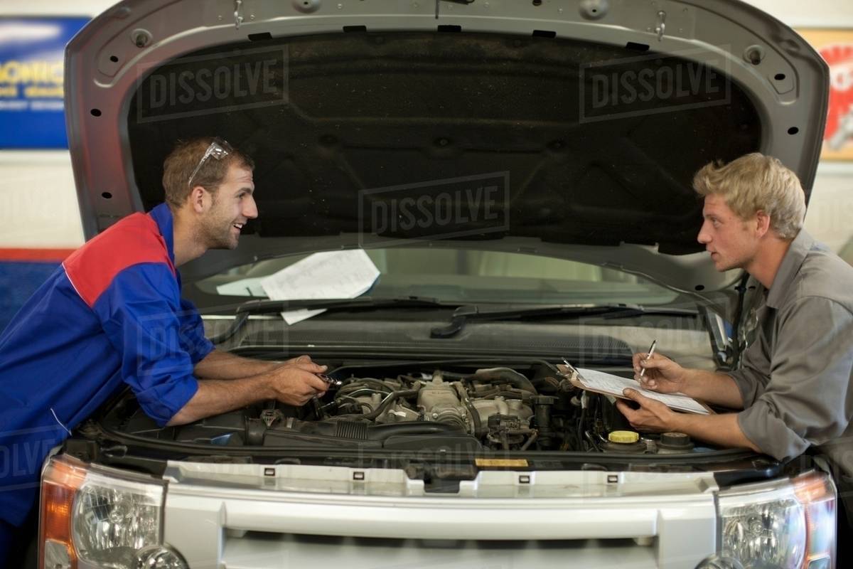 Car mechanics discussing and analyzing car repair - Royalty-free Stock ...