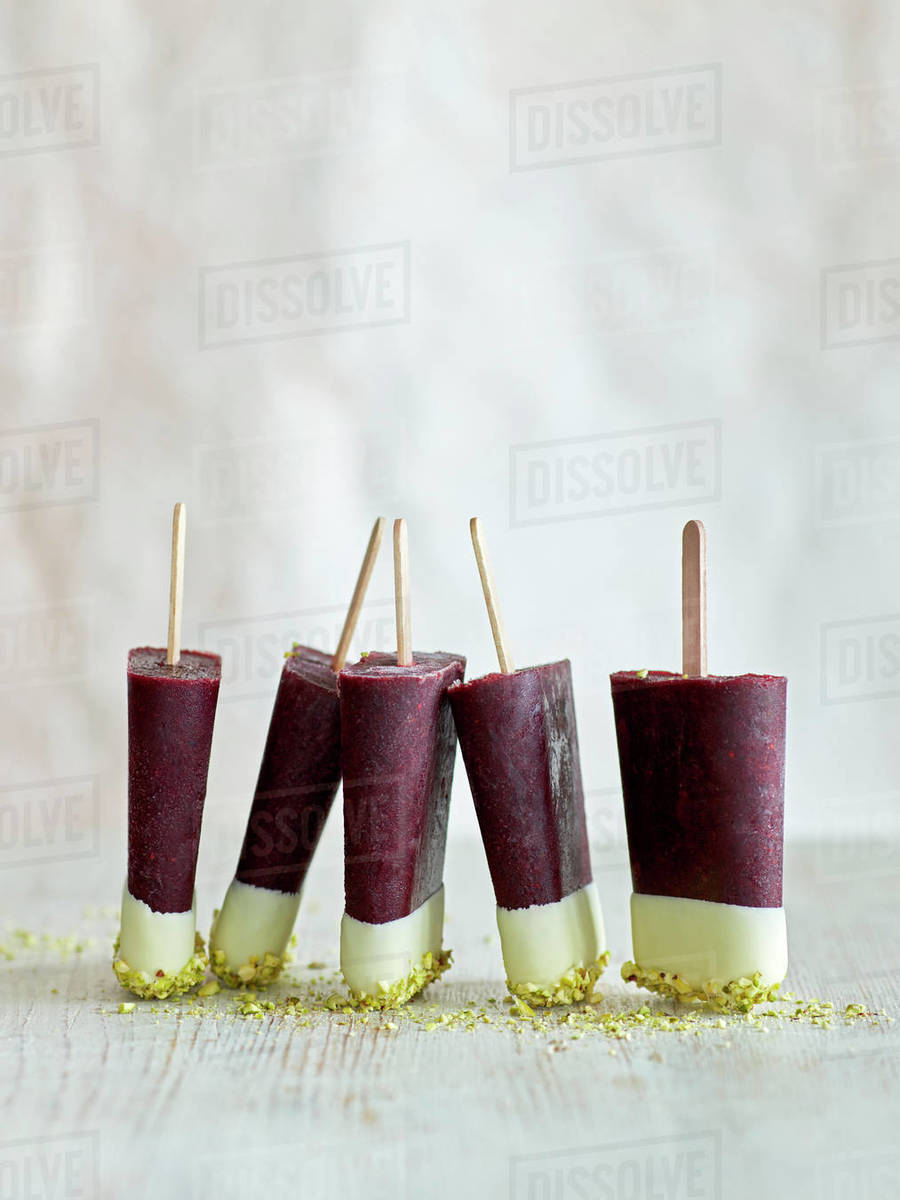 Tri-coloured ice lollies in a row on table, white background - Stock ...