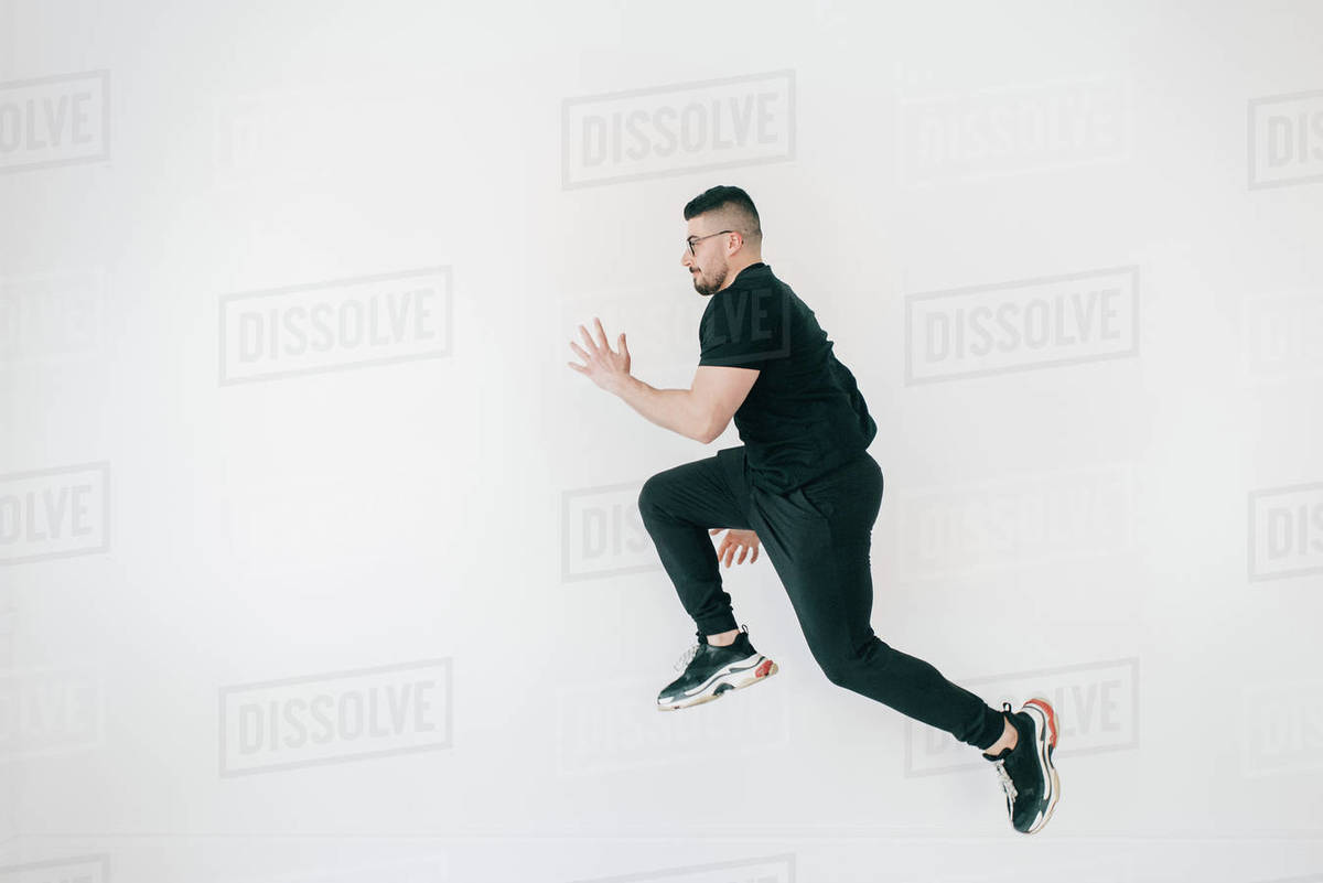 Man doing high jump against white wall - Royalty-free Stock Photo ...