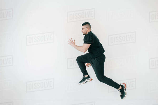 Man doing high jump against white wall - Stock Photo - Dissolve