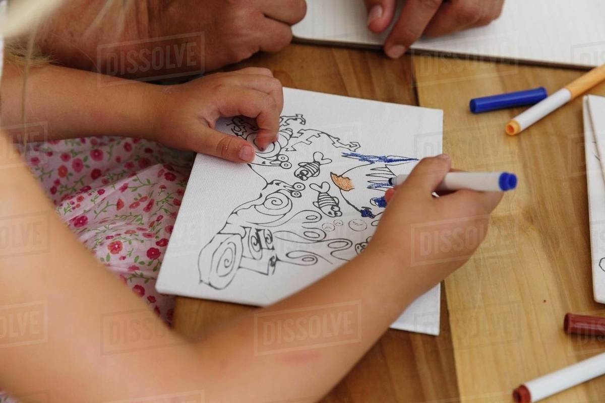 Child colouring a picture on a table - Stock Photo - Dissolve