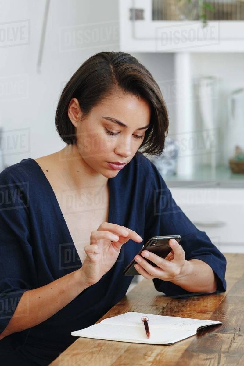 Businesswoman using cellular phone in office - Stock Photo - Dissolve
