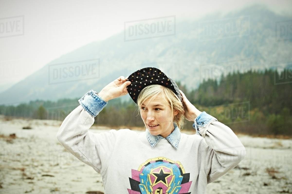 Woman putting cap headwear on - Stock Photo - Dissolve