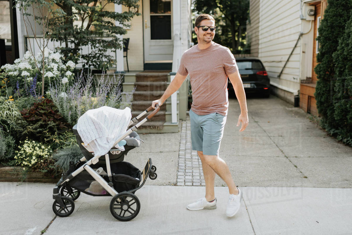 Father pushing baby carriage on pavement - Royalty-free Stock Photo ...