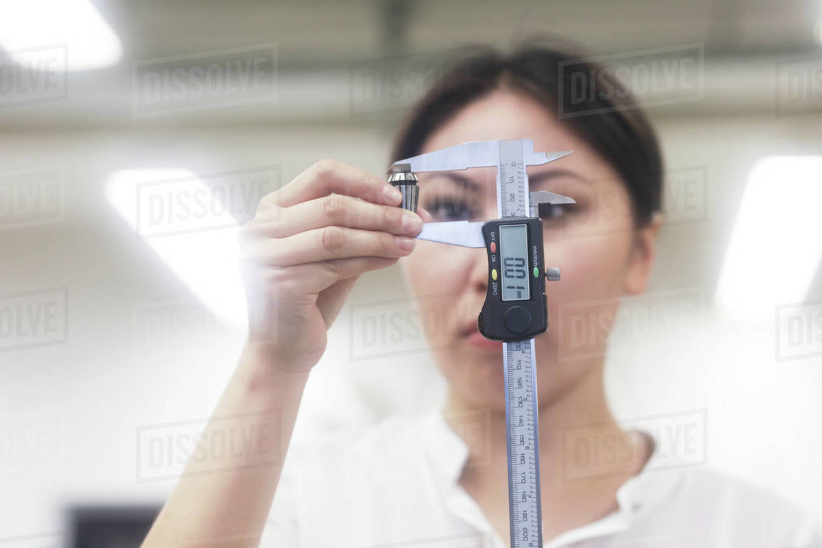 Asian woman measuring piece of gadget in office - Royalty-free Stock ...