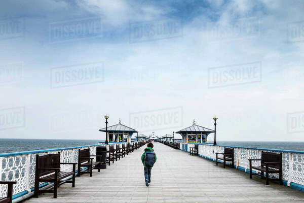 Boy taking walk along a pier at the seaside. - Royalty-free Stock Photo ...
