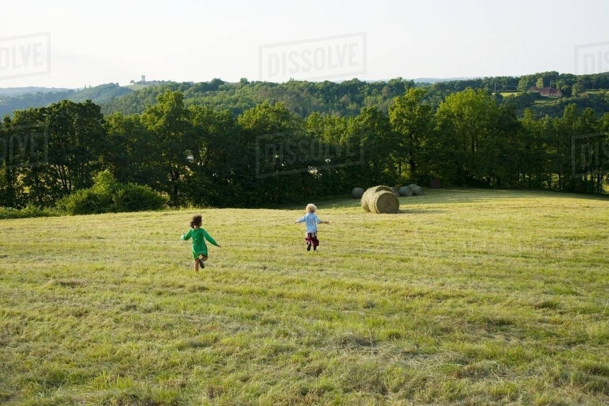 Boy and girl running down a field - Royalty-free Stock Photo | Dissolve