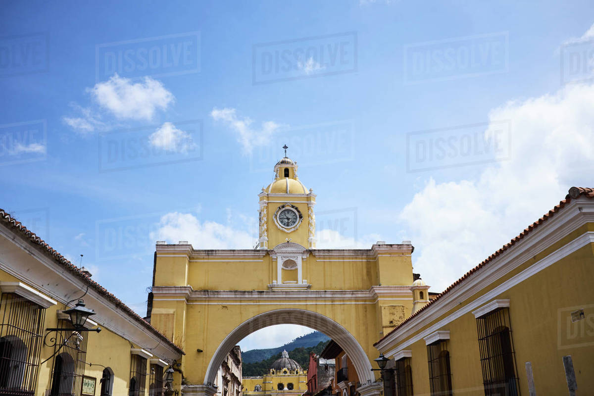 View of historic yellow clock tower over Santa Catalina Arch, Antigua ...