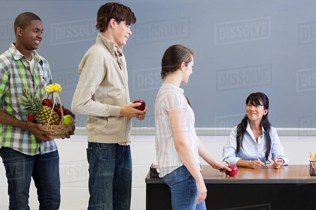 High school student giving teacher an apple - Stock Photo - Dissolve
