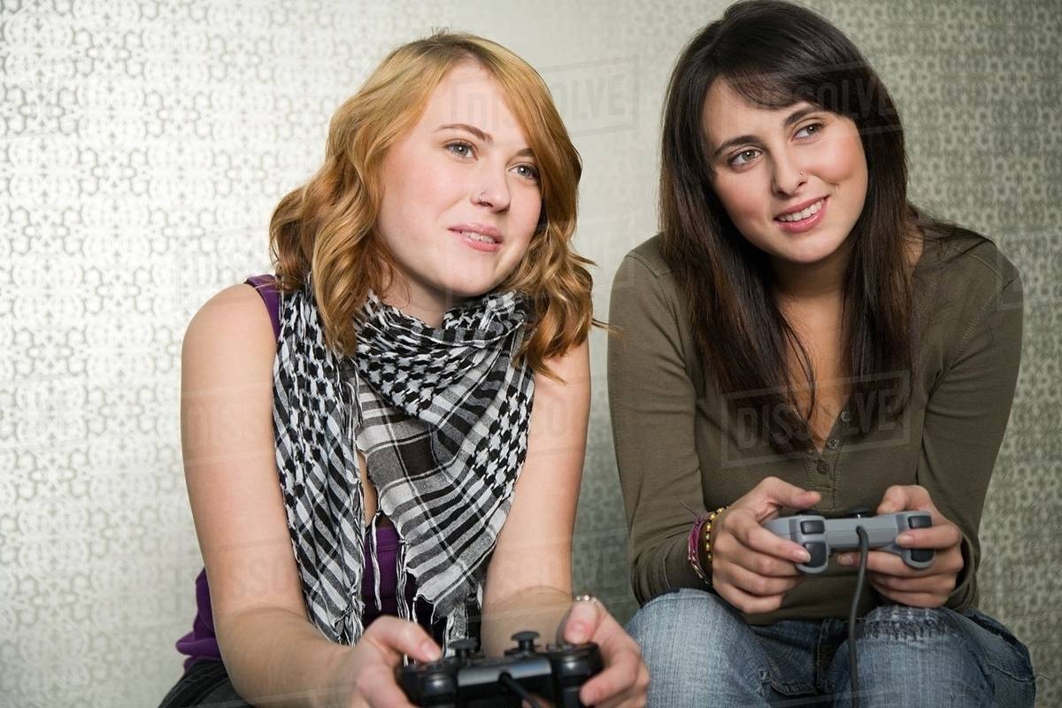Teenage girls playing on games console - Stock Photo - Dissolve