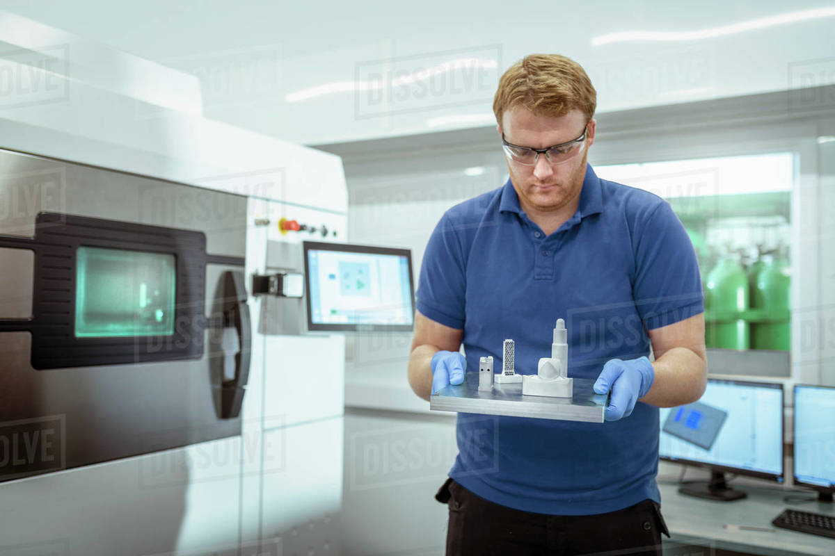 Man holding metal 3d printed objects in laboratory - Stock Photo - Dissolve