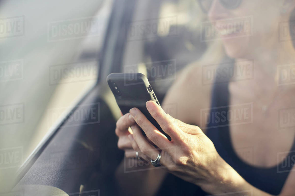 Smiling mature woman using smartphone in car - Royalty-free Stock Photo ...