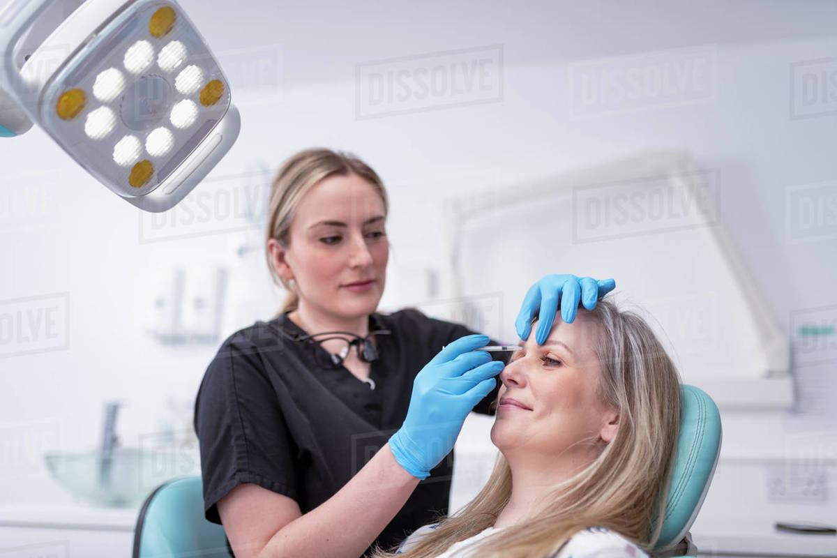 Cosmetic nurse injecting botox into patient in dental surgery - Royalty ...