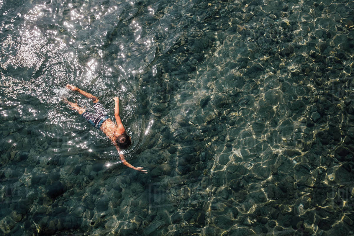 Boy (12-13) swimming in lake - Stock Photo - Dissolve