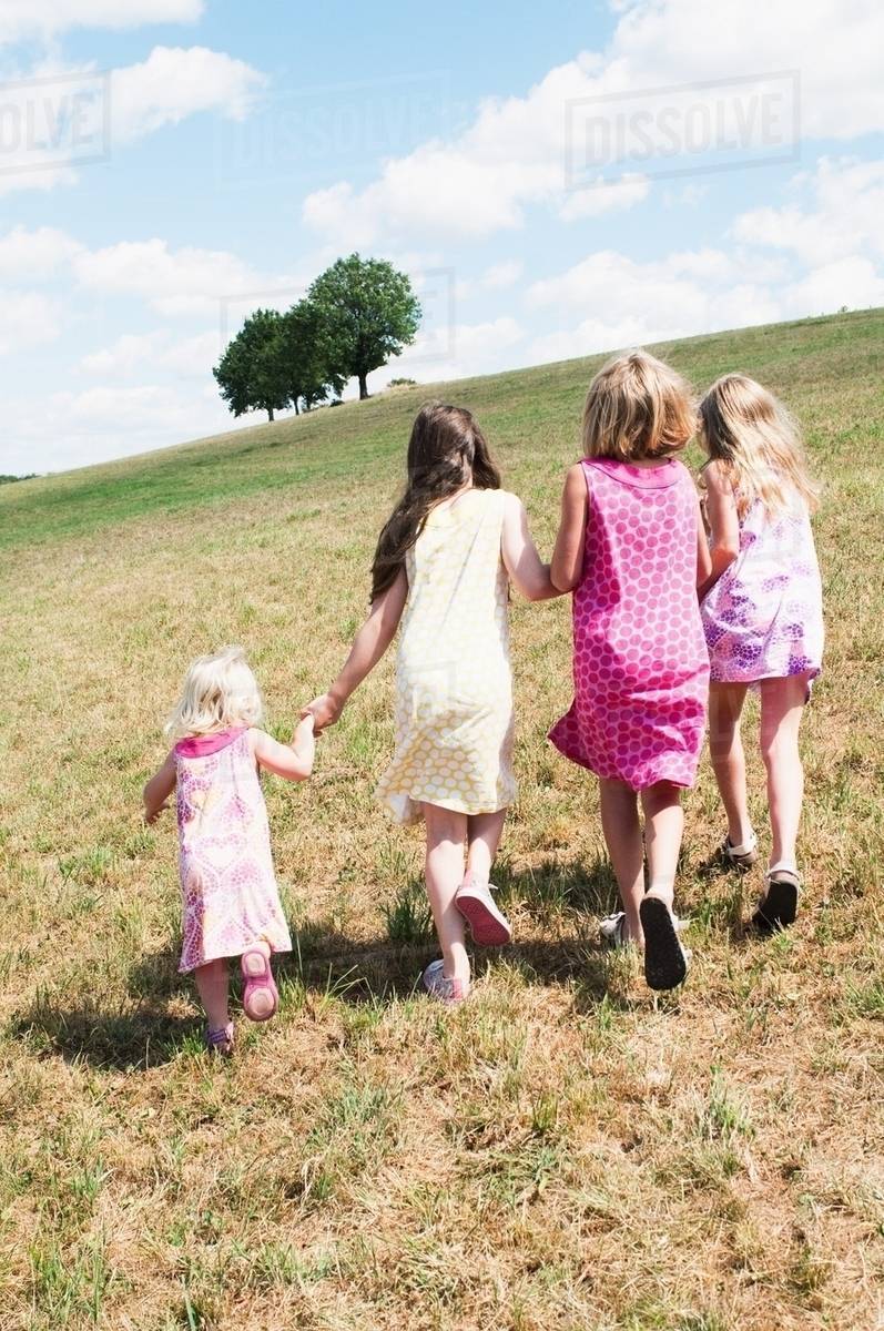 Four girls walking in field - Royalty-free Stock Photo | Dissolve