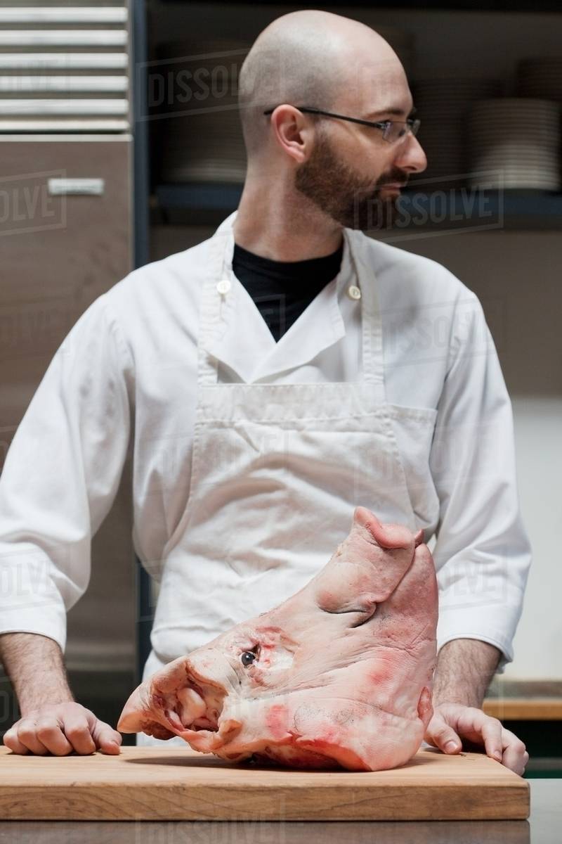 Butcher preparing with head of pig - Stock Photo - Dissolve