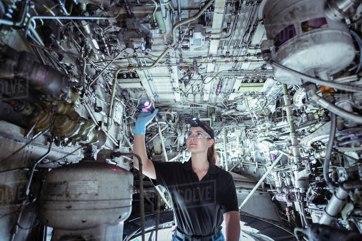 Female apprentice aircraft maintenance engineer inspecting wheel well ...