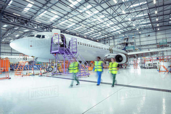 Aircraft maintenance engineers walking past aircraft in maintenance ...