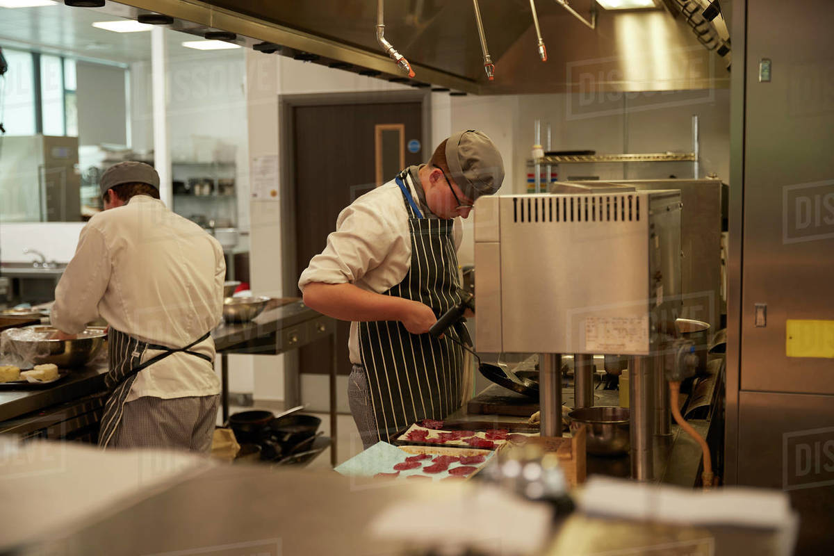 Young cooks working in kitchen - Royalty-free Stock Photo | Dissolve