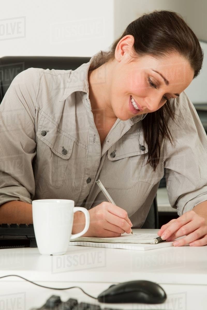Female office worker writing in a notebook - Royalty-free Stock Photo ...