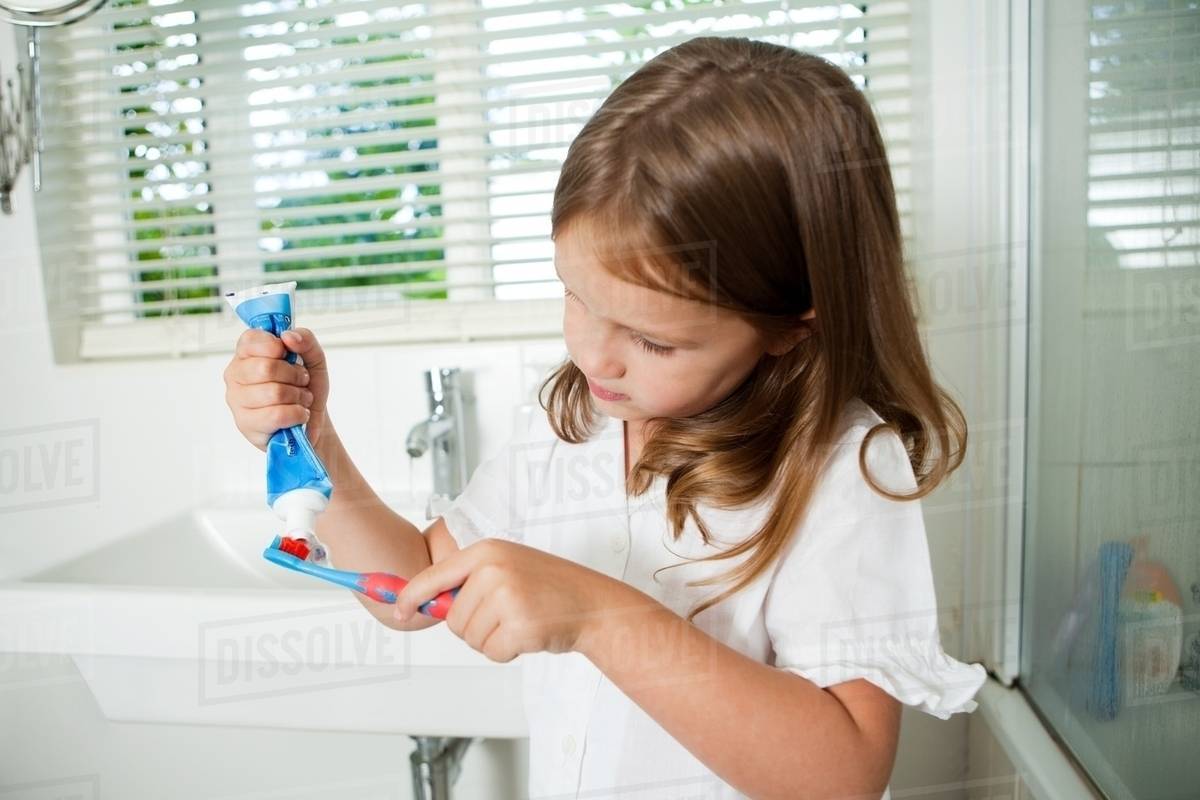 Girl applying toothpaste to brush in bathroom - Royalty-free Stock ...