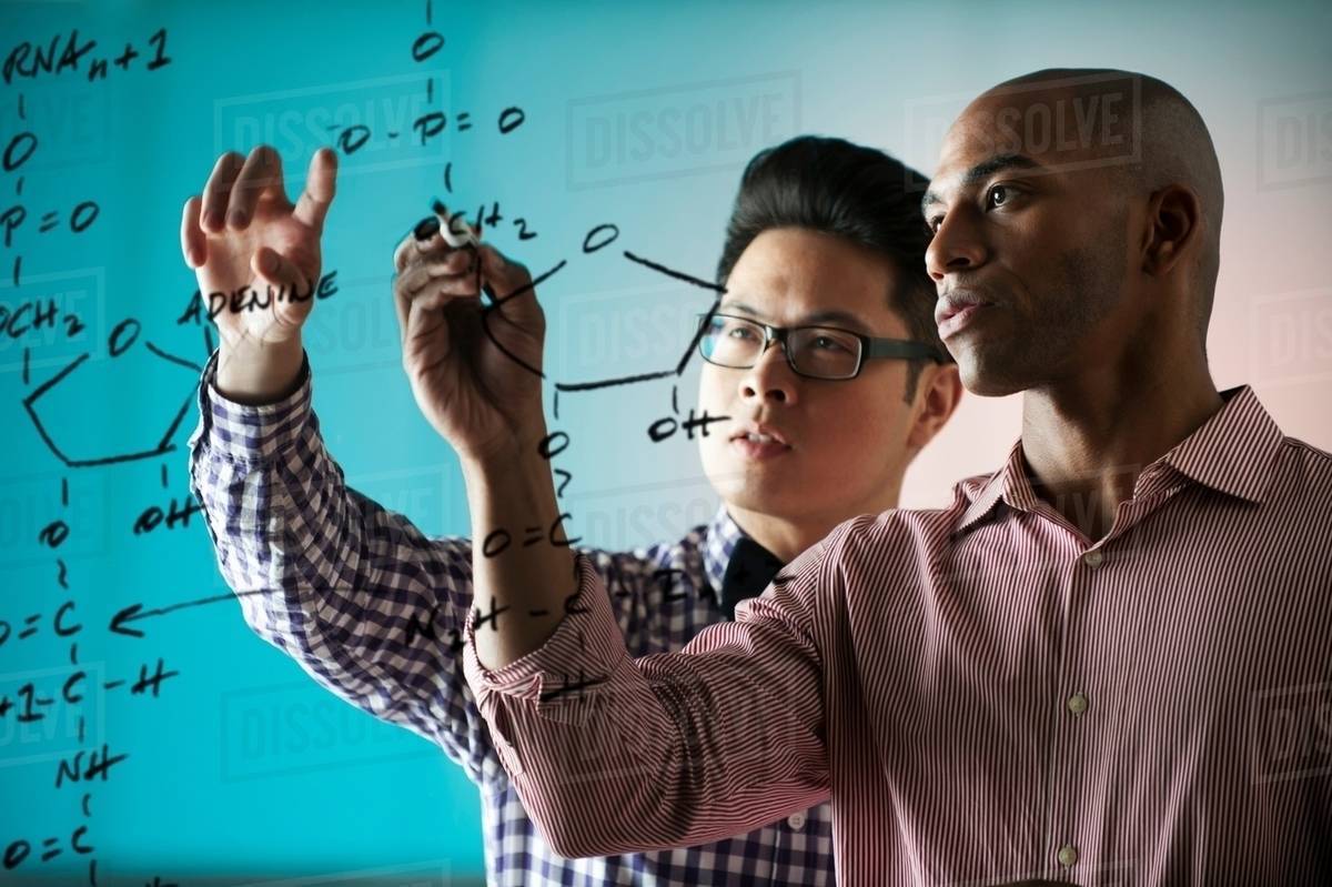 Two people writing formula on window - Royalty-free Stock Photo | Dissolve