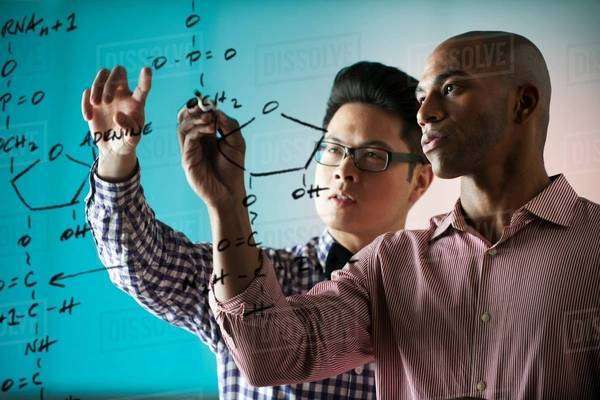 Two people writing formula on window - Royalty-free Stock Photo | Dissolve