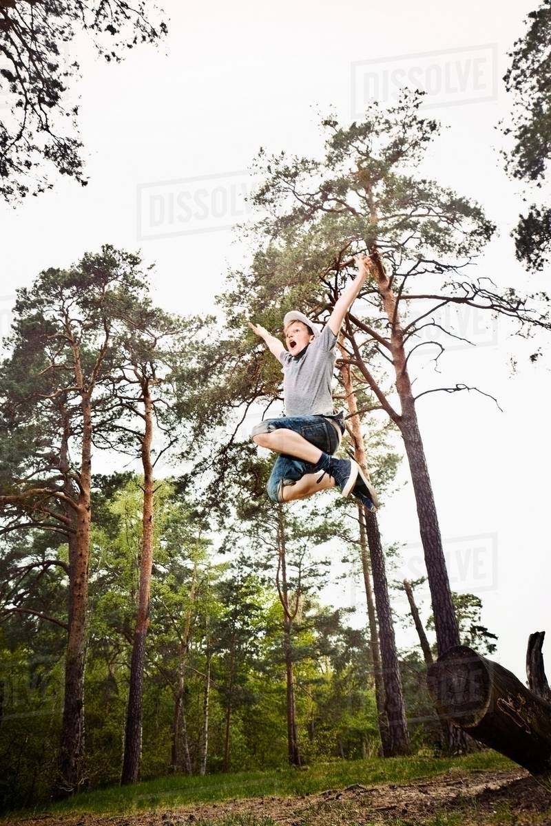 Boy jumping in forest - Stock Photo - Dissolve