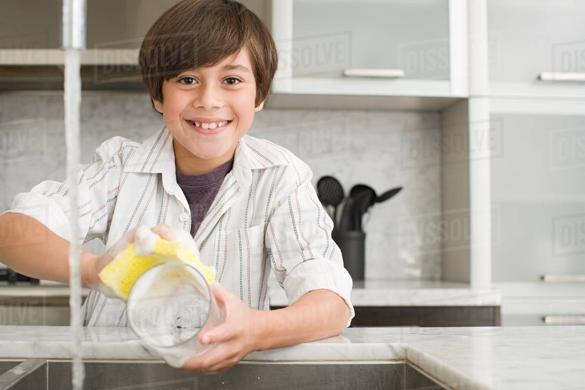 Smiling boy washing up - Stock Photo - Dissolve